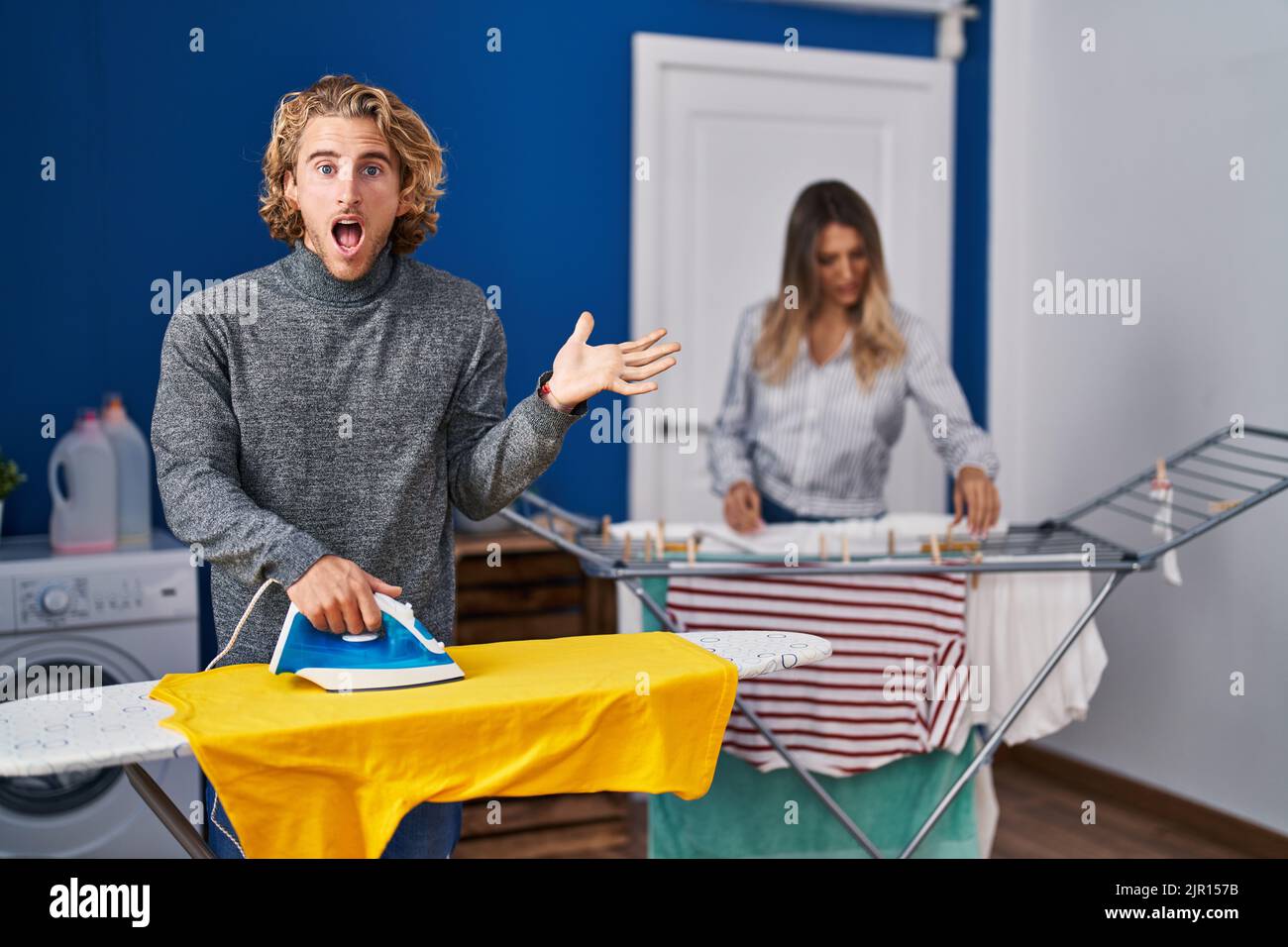 Couple ironing clothes at laundry room celebrating victory with happy ...