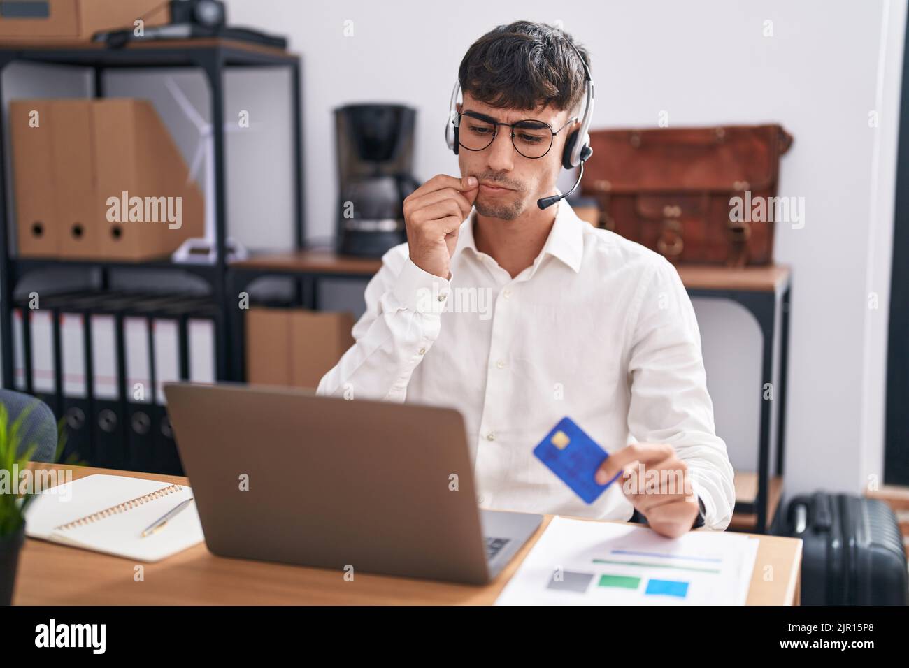 Young hispanic man working using computer laptop holding credit card ... Young hispanic man working using computer laptop holding credit card ...