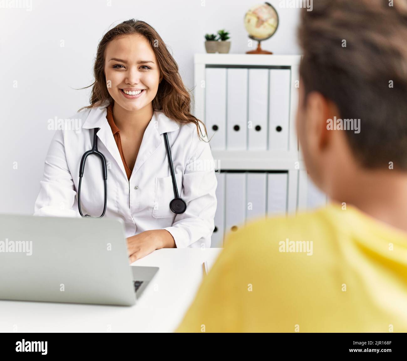 Young doctor woman with patient at the clinic looking positive and ...
