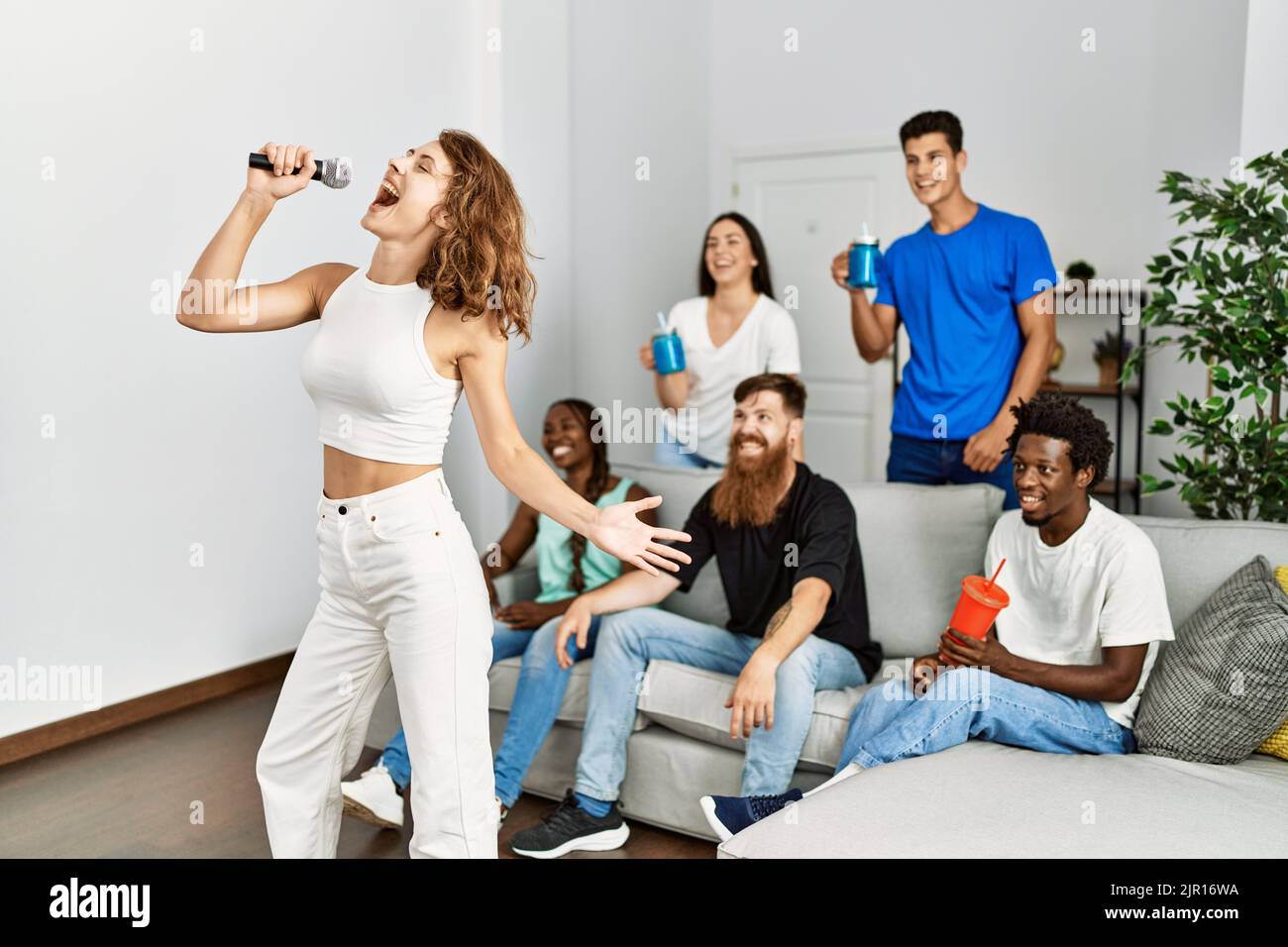 Group of young friends having party singing song using microphone at ...