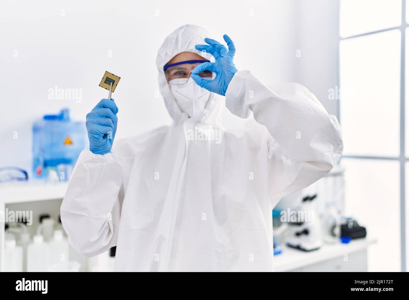 Young blonde woman holding cpu computer processor at laboratory smiling ...