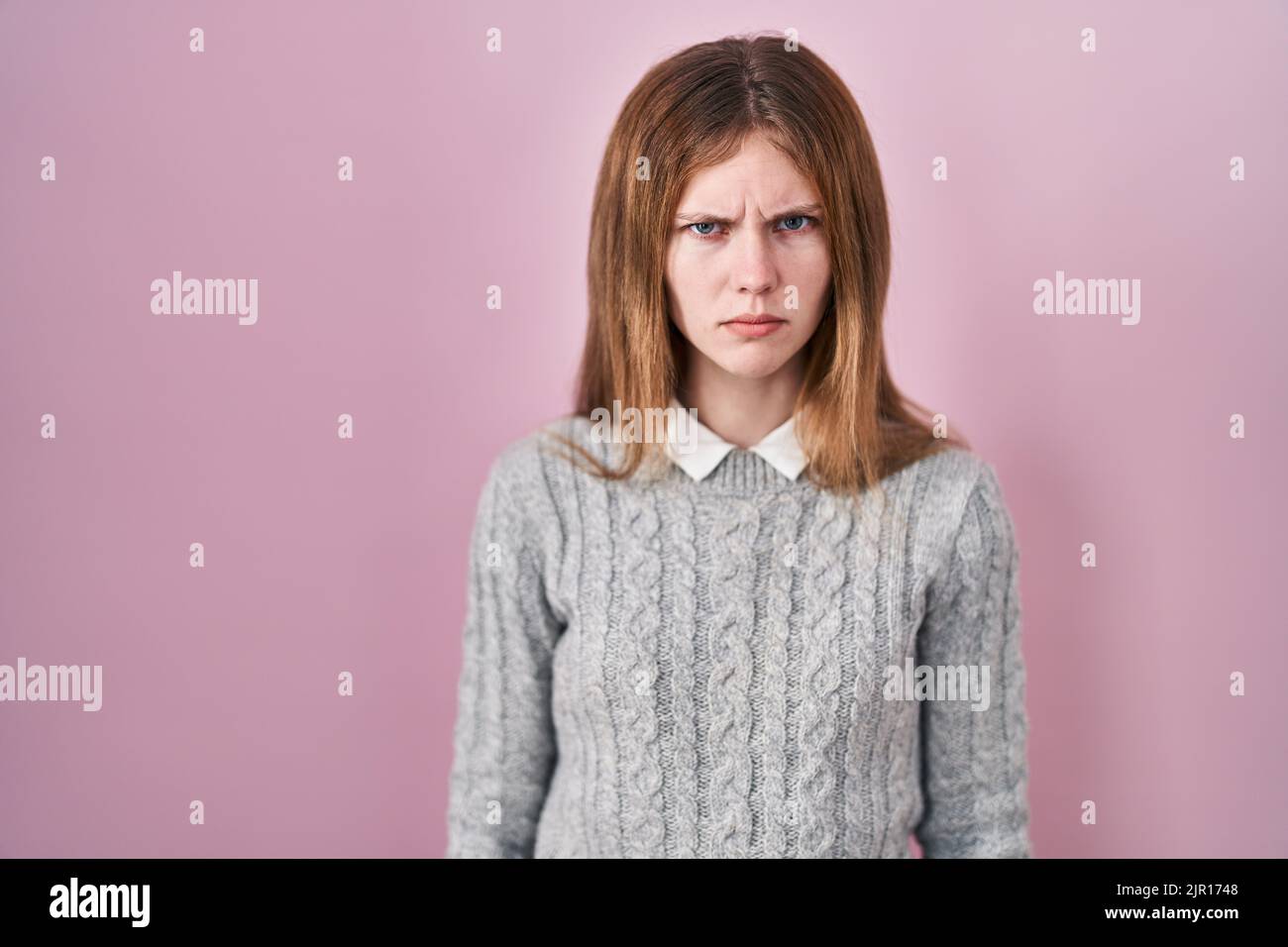 Beautiful woman standing over pink background skeptic and nervous ...