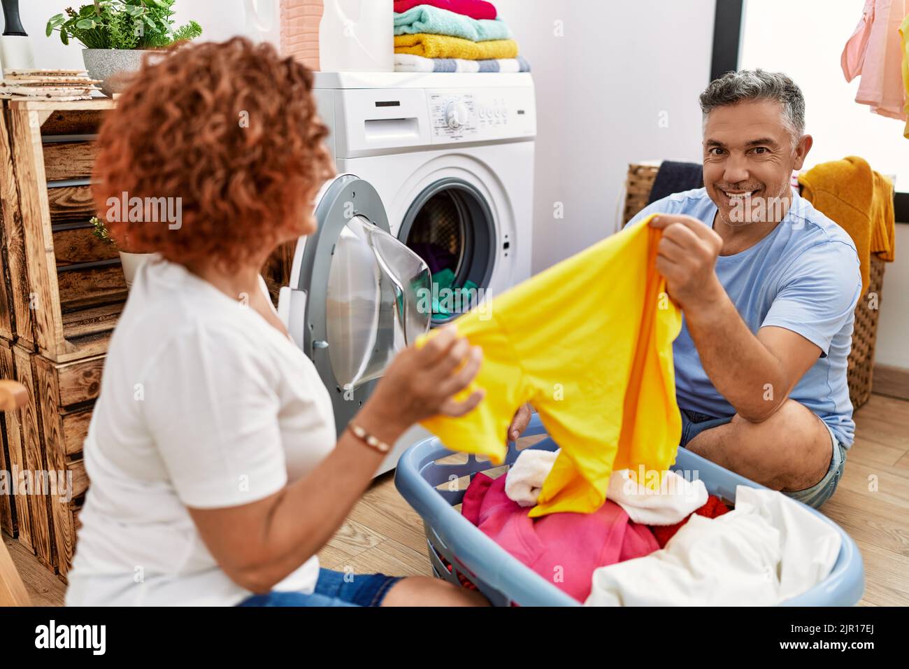 Middle age man and woman couple holding t shirt washing clothes at ...