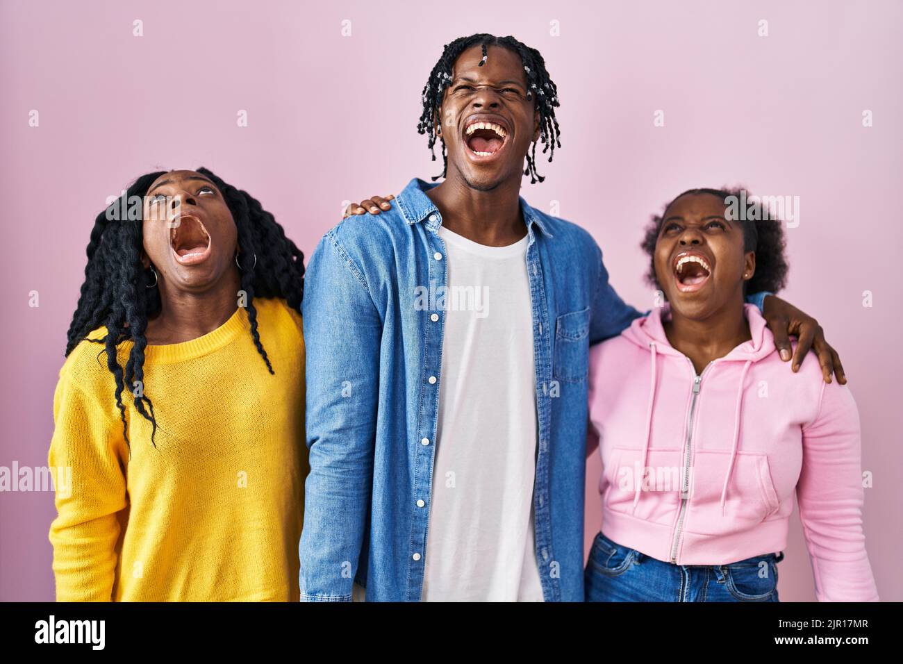 Group of three young black people standing together over pink ...