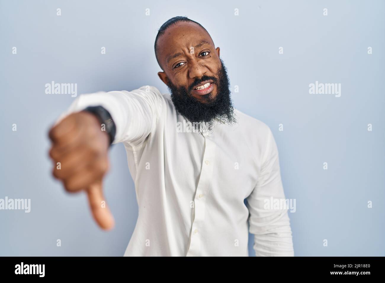 African American Man Standing Over Blue Background Looking Unhappy And