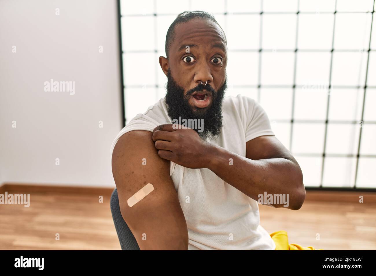African american man getting vaccine showing arm with band aid scared ...