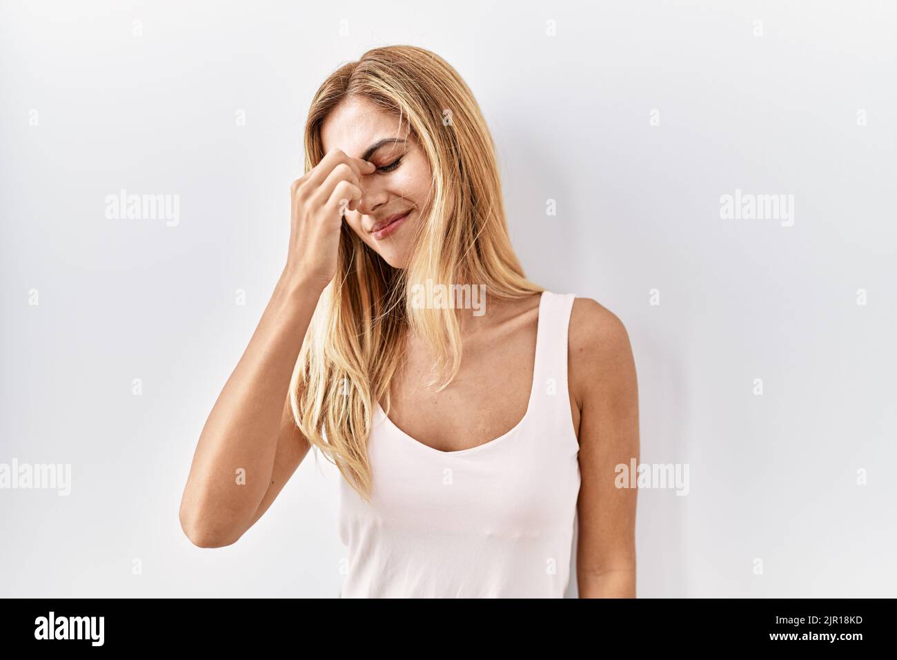 Blonde beautiful young woman standing over white isolated background ...