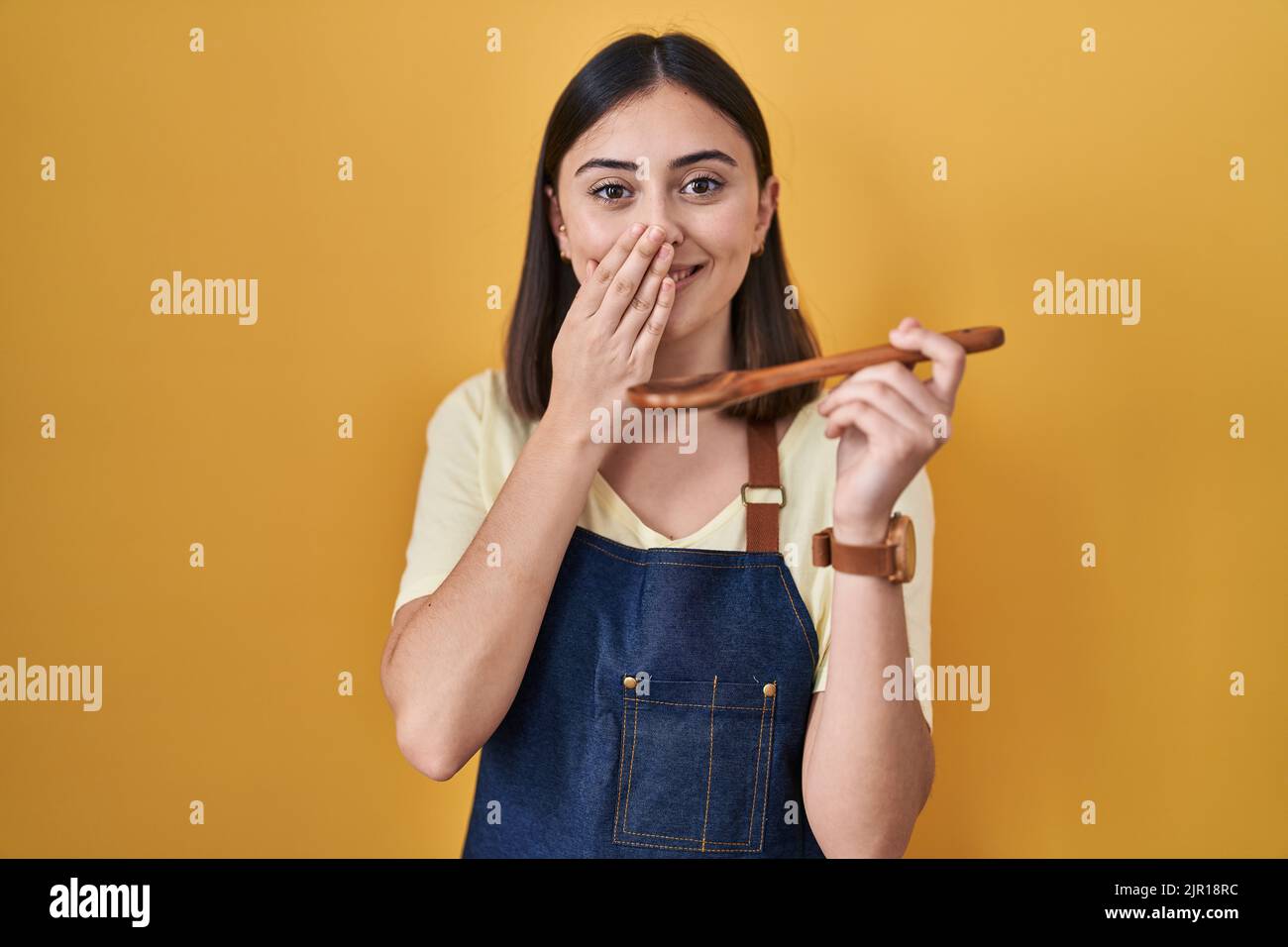 Hispanic girl eating healthy wooden spoon laughing and embarrassed ...