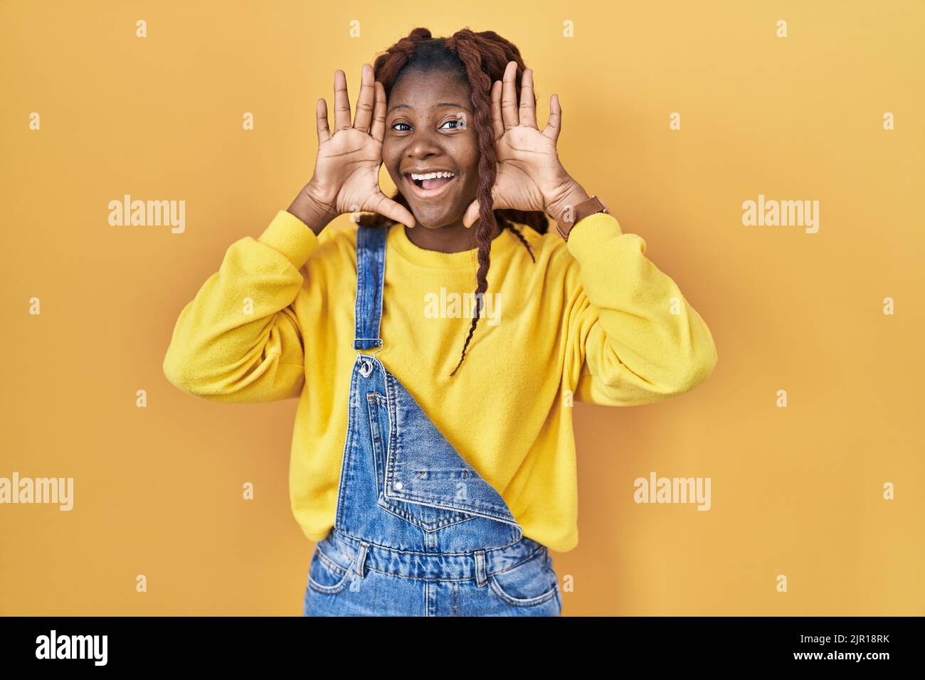 African woman standing over yellow background smiling cheerful playing ...