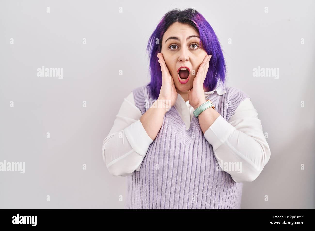 Plus size woman wit purple hair standing over white background afraid ...