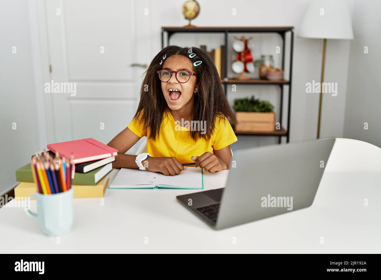 Young african american girl doing homework at home angry and mad ...