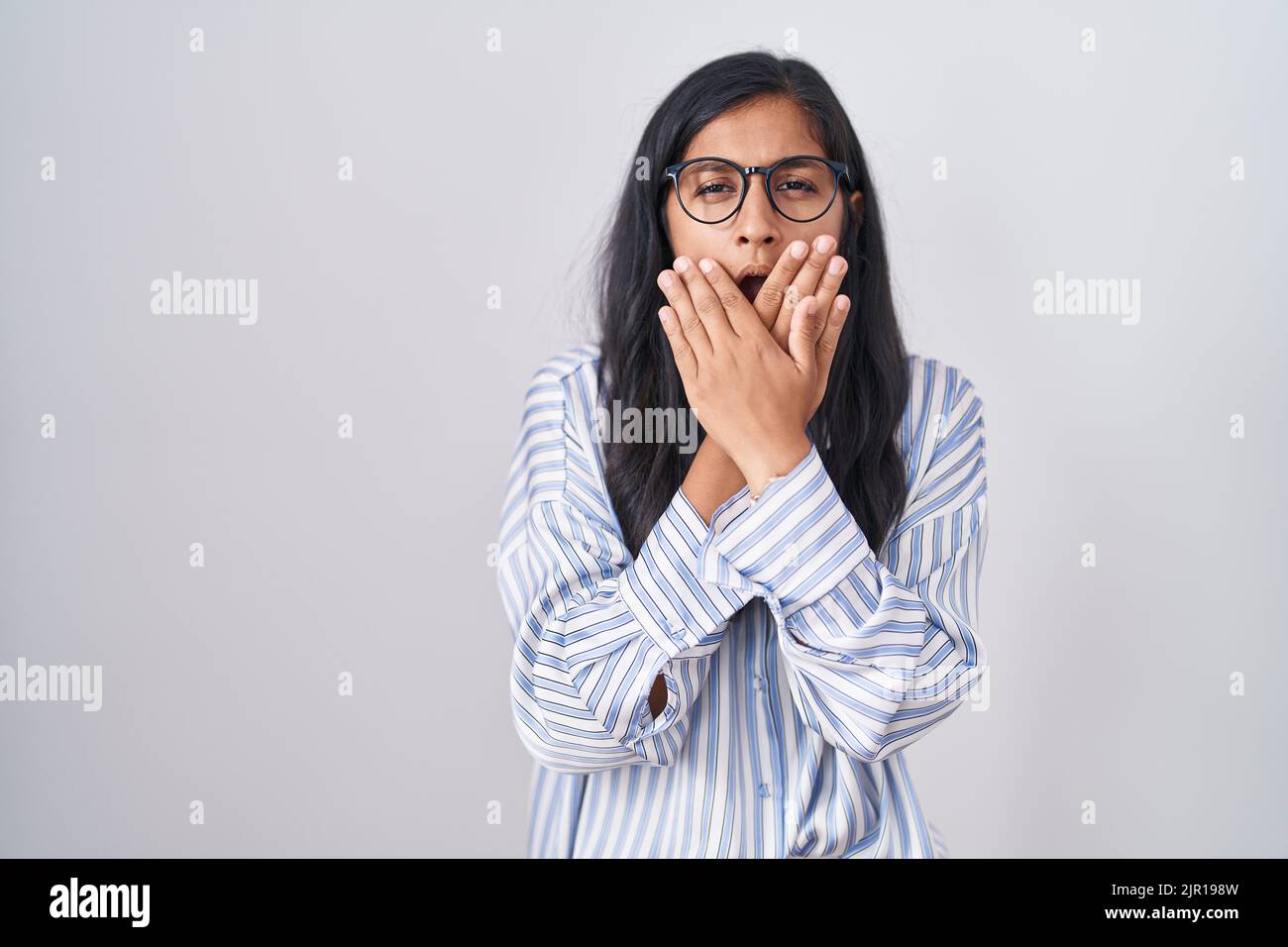 Young hispanic woman wearing glasses shocked covering mouth with hands ...