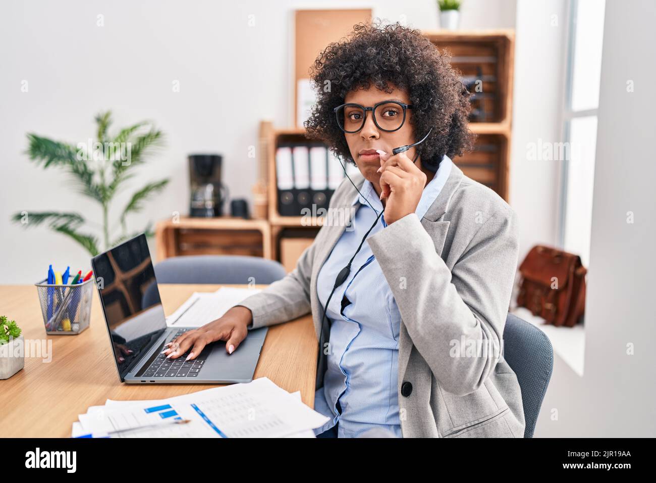 Black woman with curly hair wearing call center agent headset at the ...