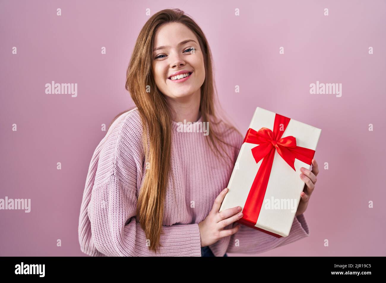Young caucasian woman holding gift smiling and laughing hard out loud ...