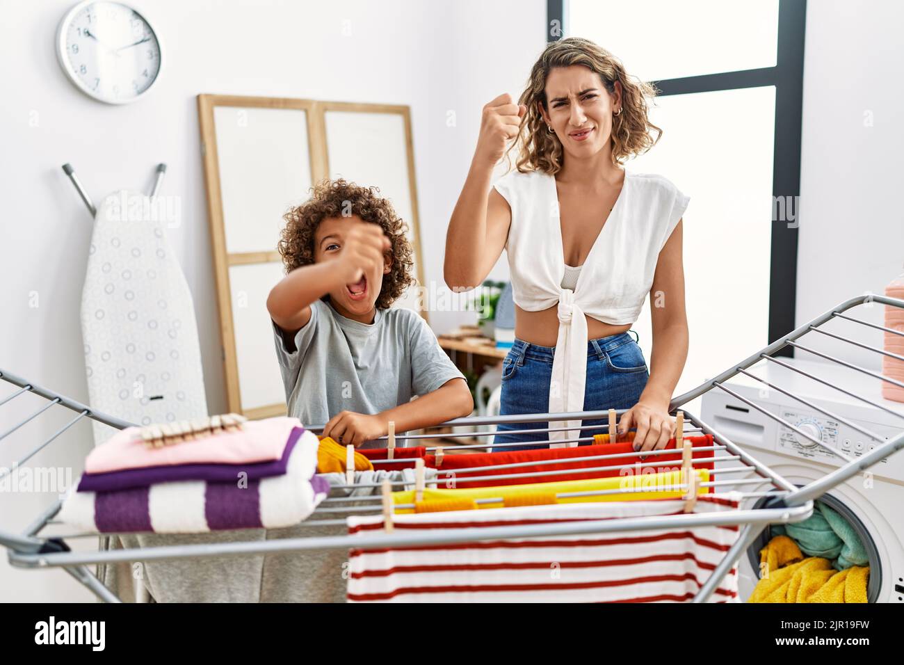 Young woman and son doing laundry at clothesline annoyed and frustrated ...