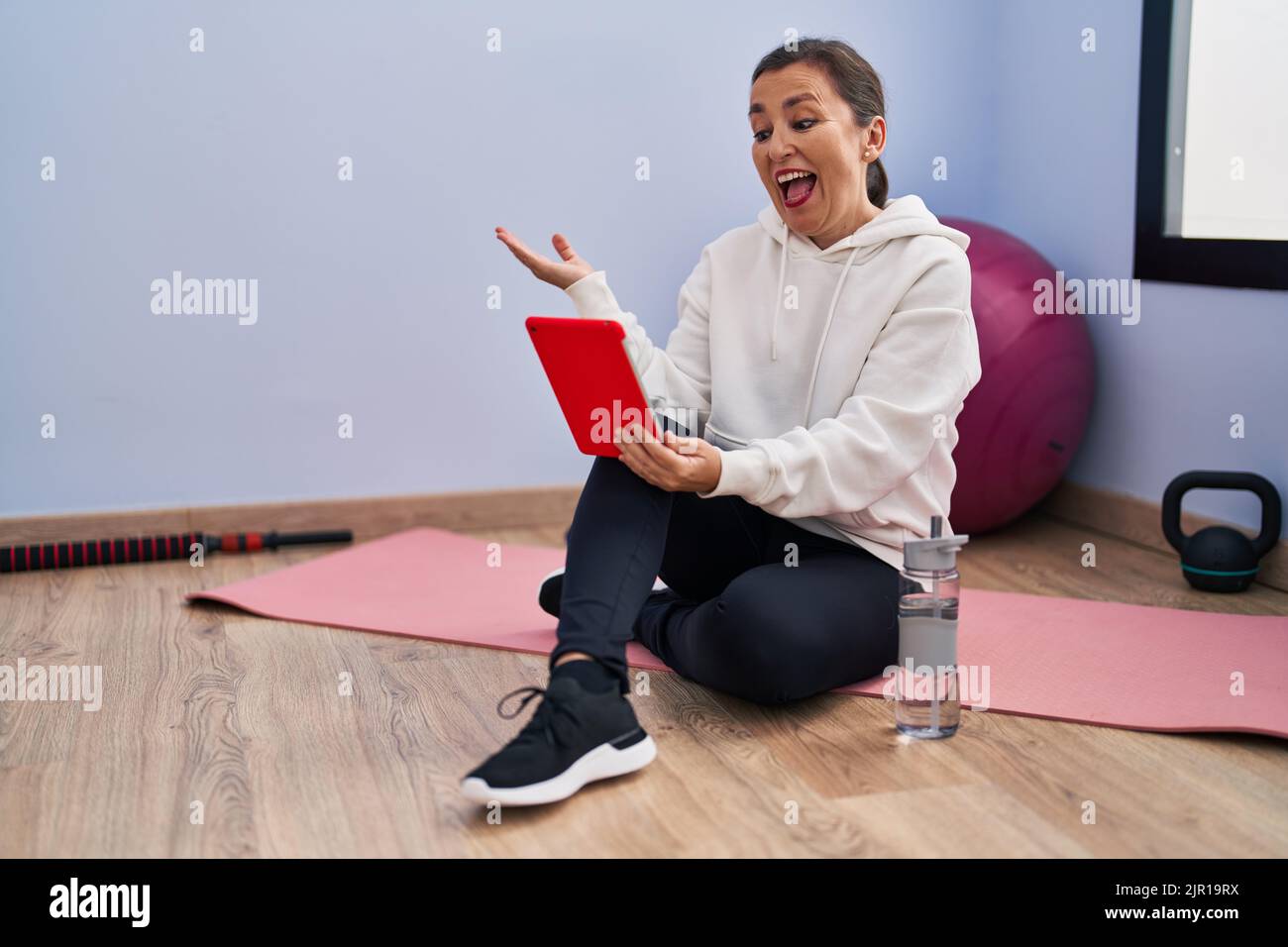Middle age hispanic woman training using tablet celebrating achievement ...