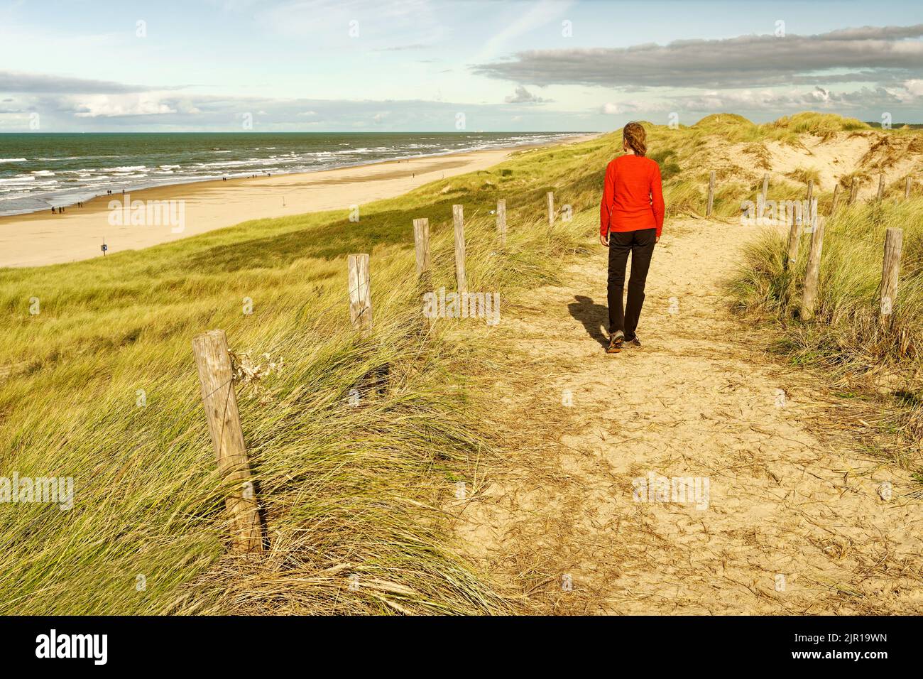 A woman walking on a beautiful sandy path along the ocean. North ...