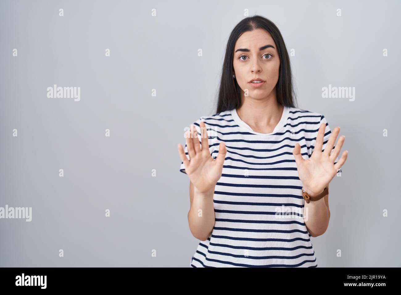 Young brunette woman wearing striped t shirt moving away hands palms ...