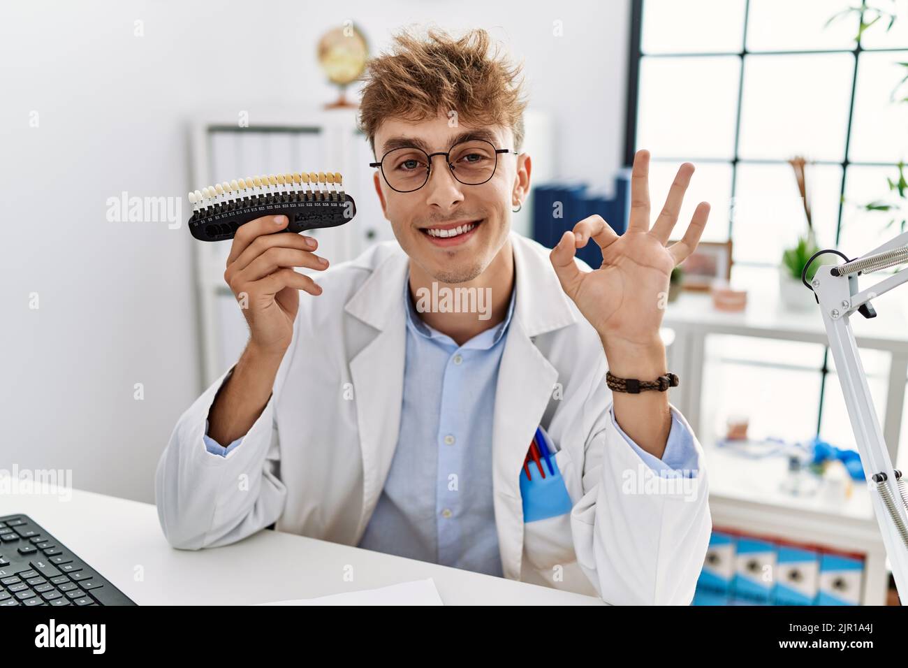 Young caucasian dentist man comparing teeth whitening at the clinic ...