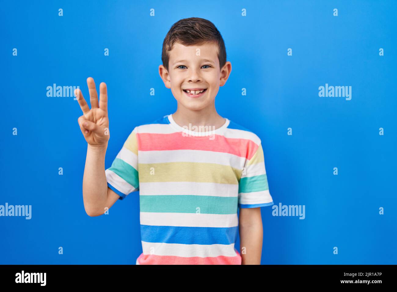 Young caucasian kid standing over blue background showing and pointing ...