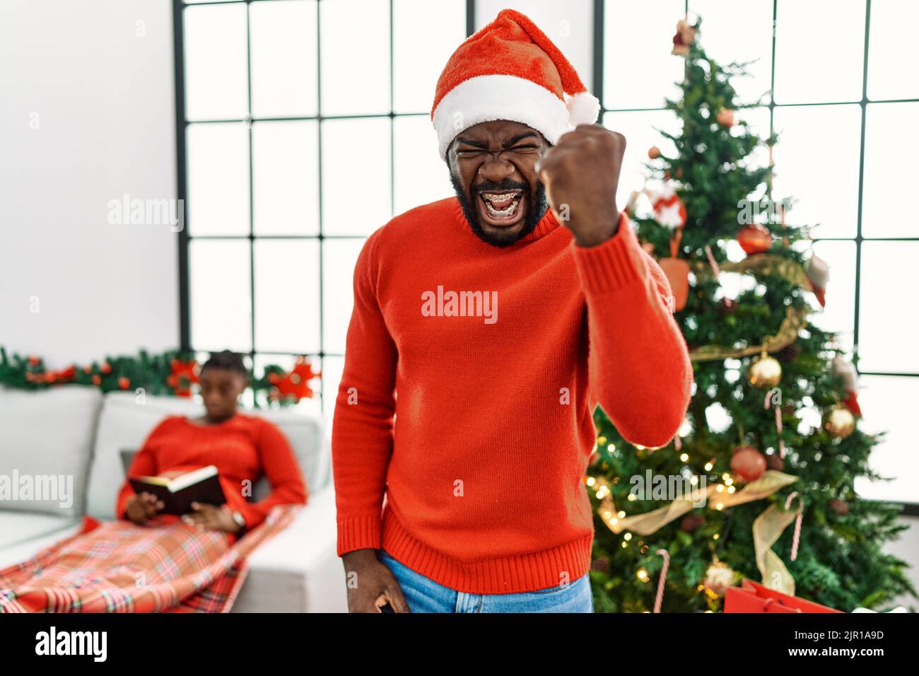 Young african american man standing by christmas tree angry and mad ...