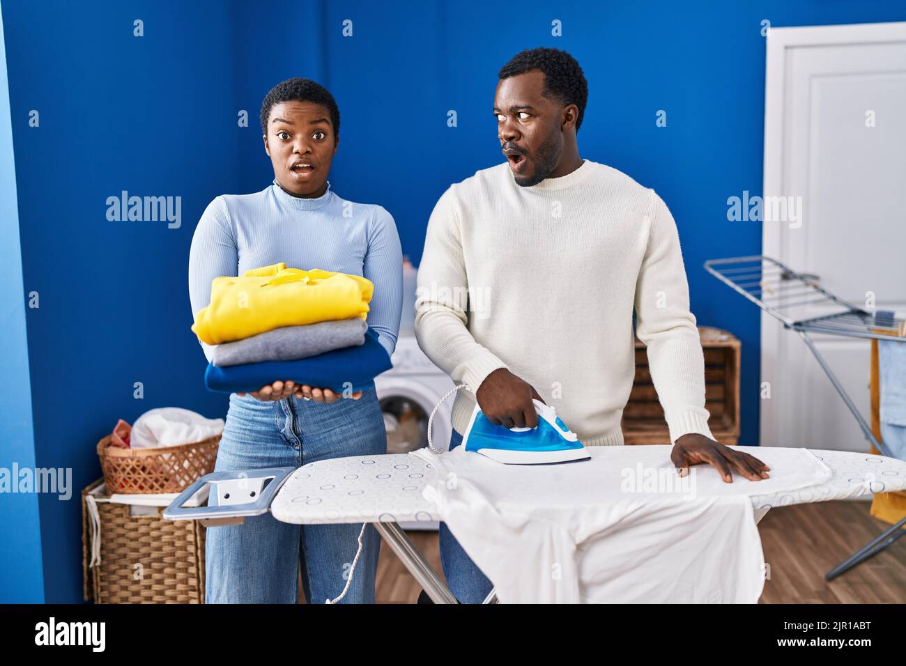 Young african american couple ironing clothes at laundry room in shock ...