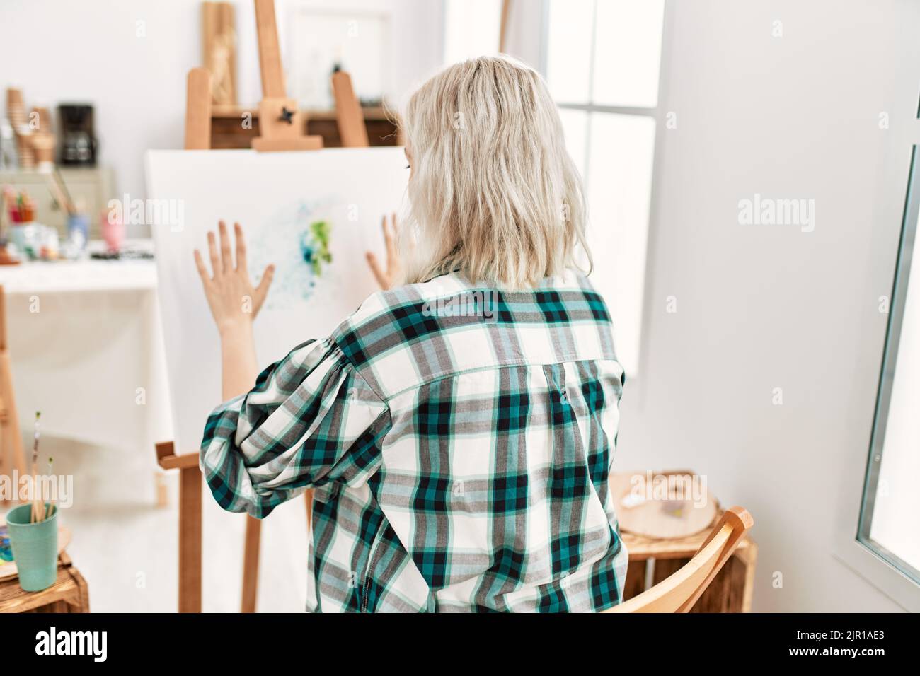 Young artist student girl on back view painting canvas with painted ...