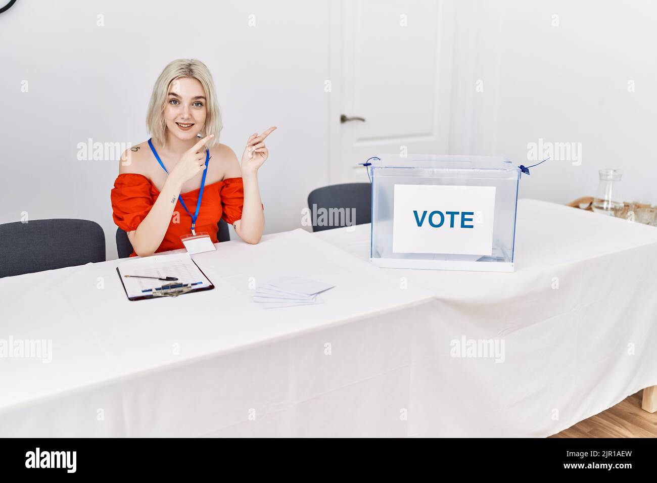 Young caucasian woman at political election sitting by ballot smiling ...