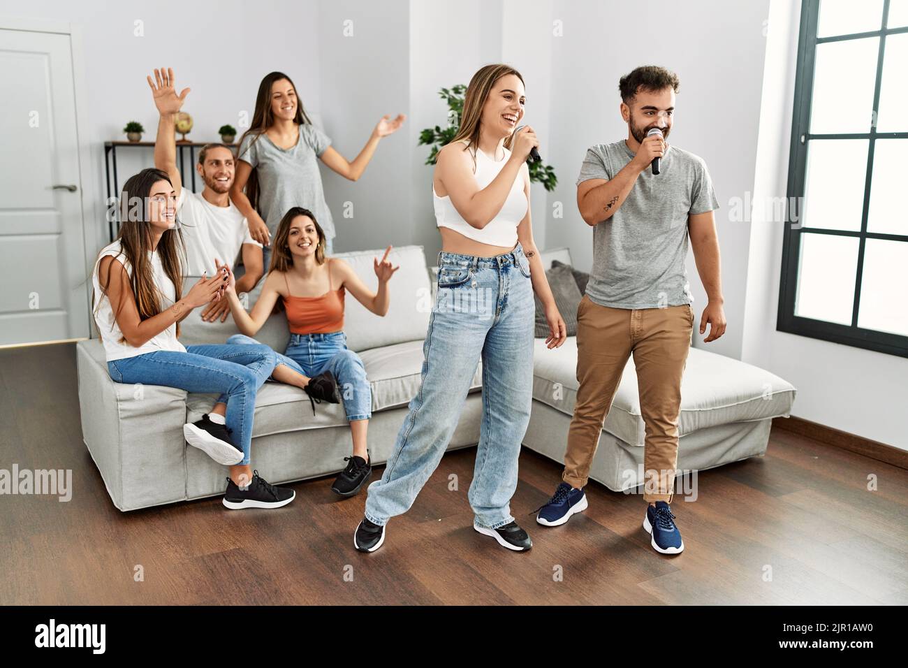 Group of young friends having party singing song using microphone at ...