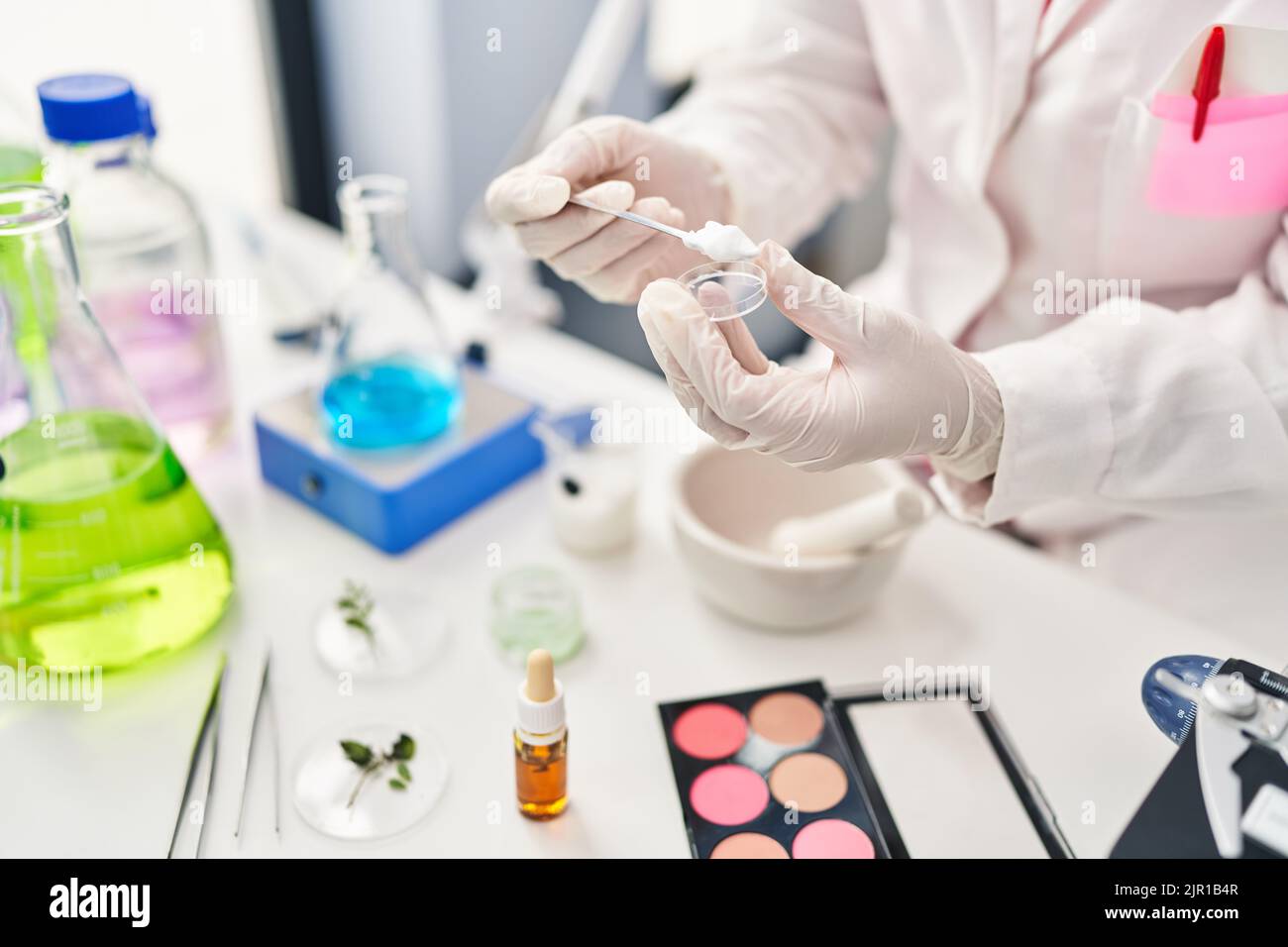 Young hispanic woman wearing scientist uniform mixing powder at ...