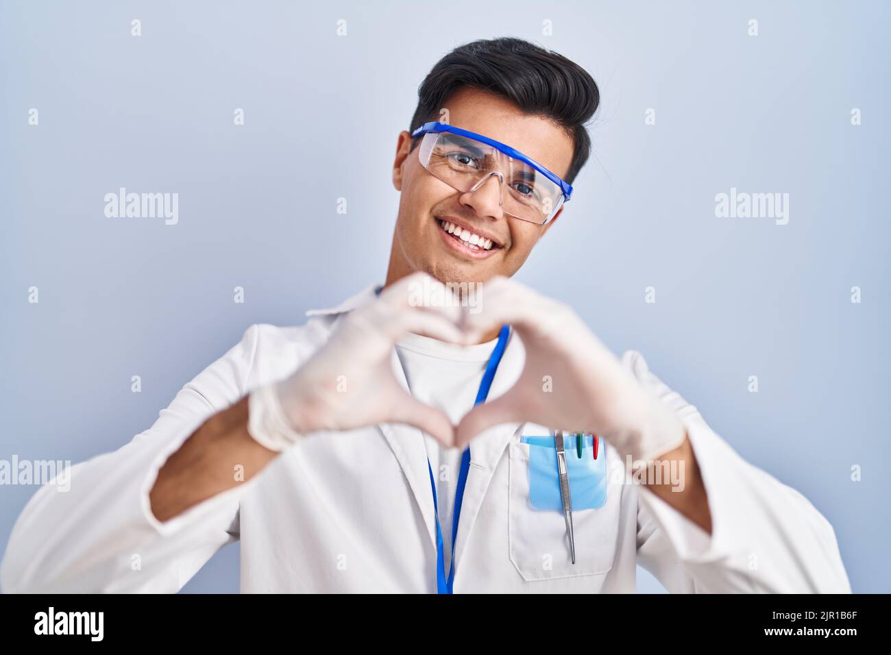 Hispanic man working as scientist smiling in love doing heart symbol ...