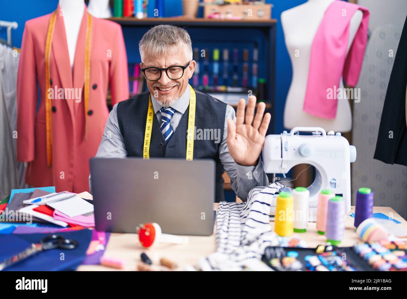 Hispanic tailor man with grey hair doing video call looking positive ...