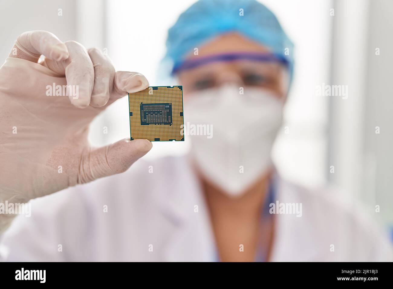 Middle age woman wearing scientist unifor and medical mask holding cpu ...