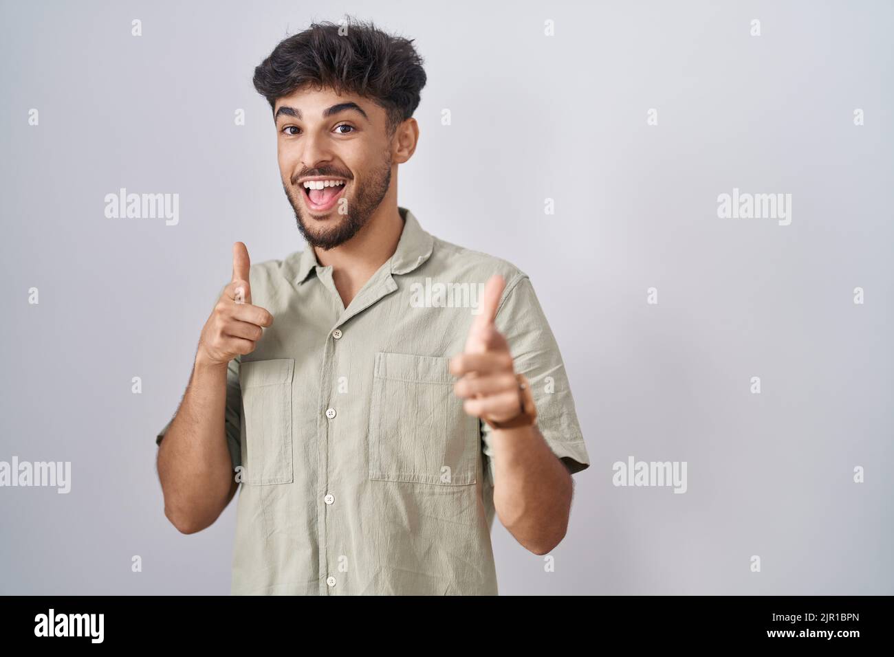 Arab man with beard standing over white background pointing fingers to ...