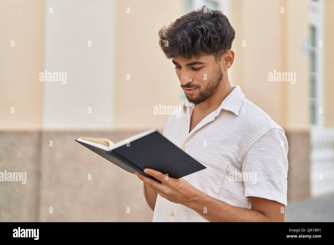 Young arab man reading book at street Stock Photo - Alamy