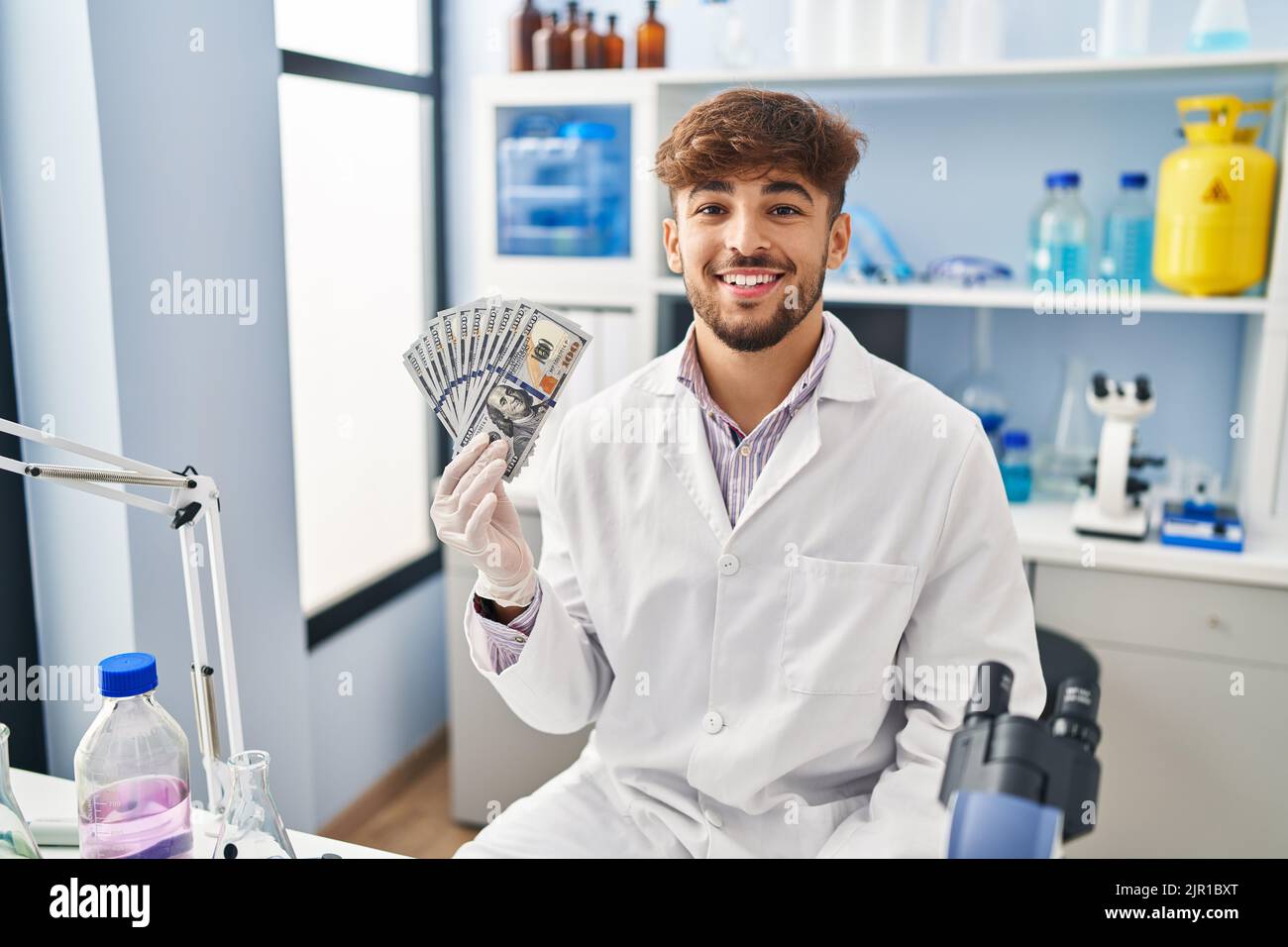 Arab man with beard working at scientist laboratory holding money ...