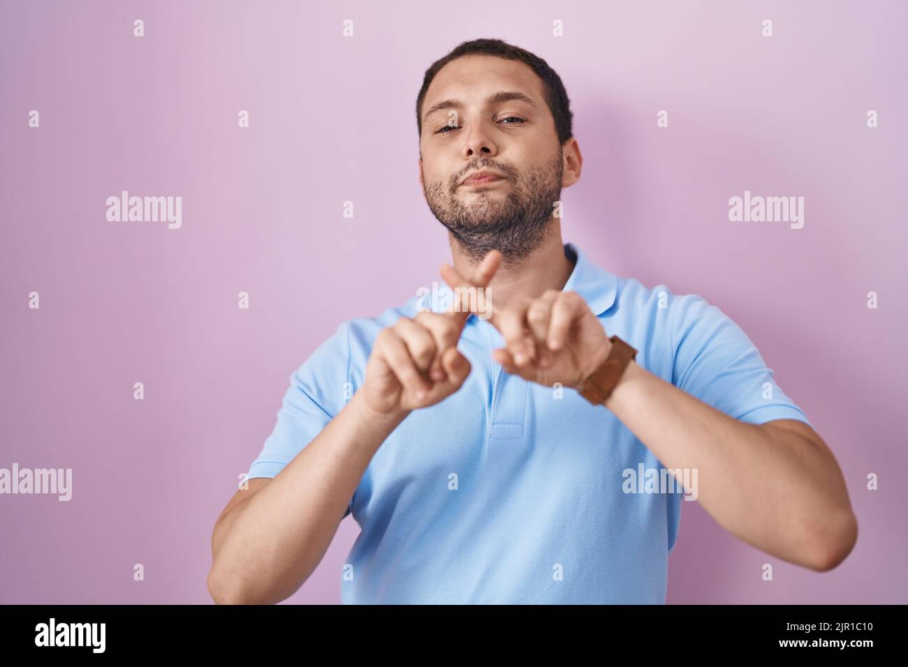 Hispanic man standing over pink background rejection expression ...