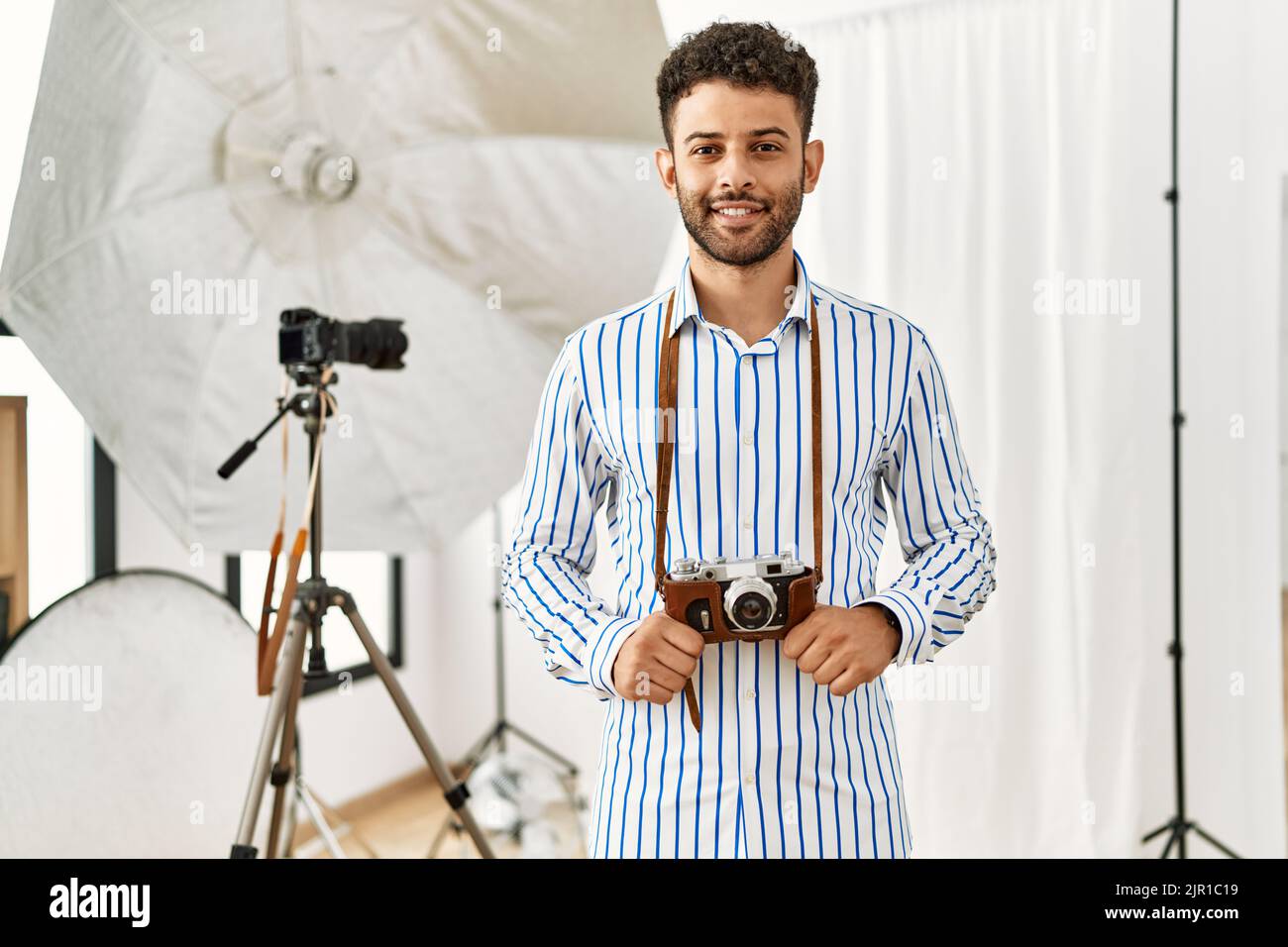 Young arab photographer man smiling happy using vintage camera at photo ...