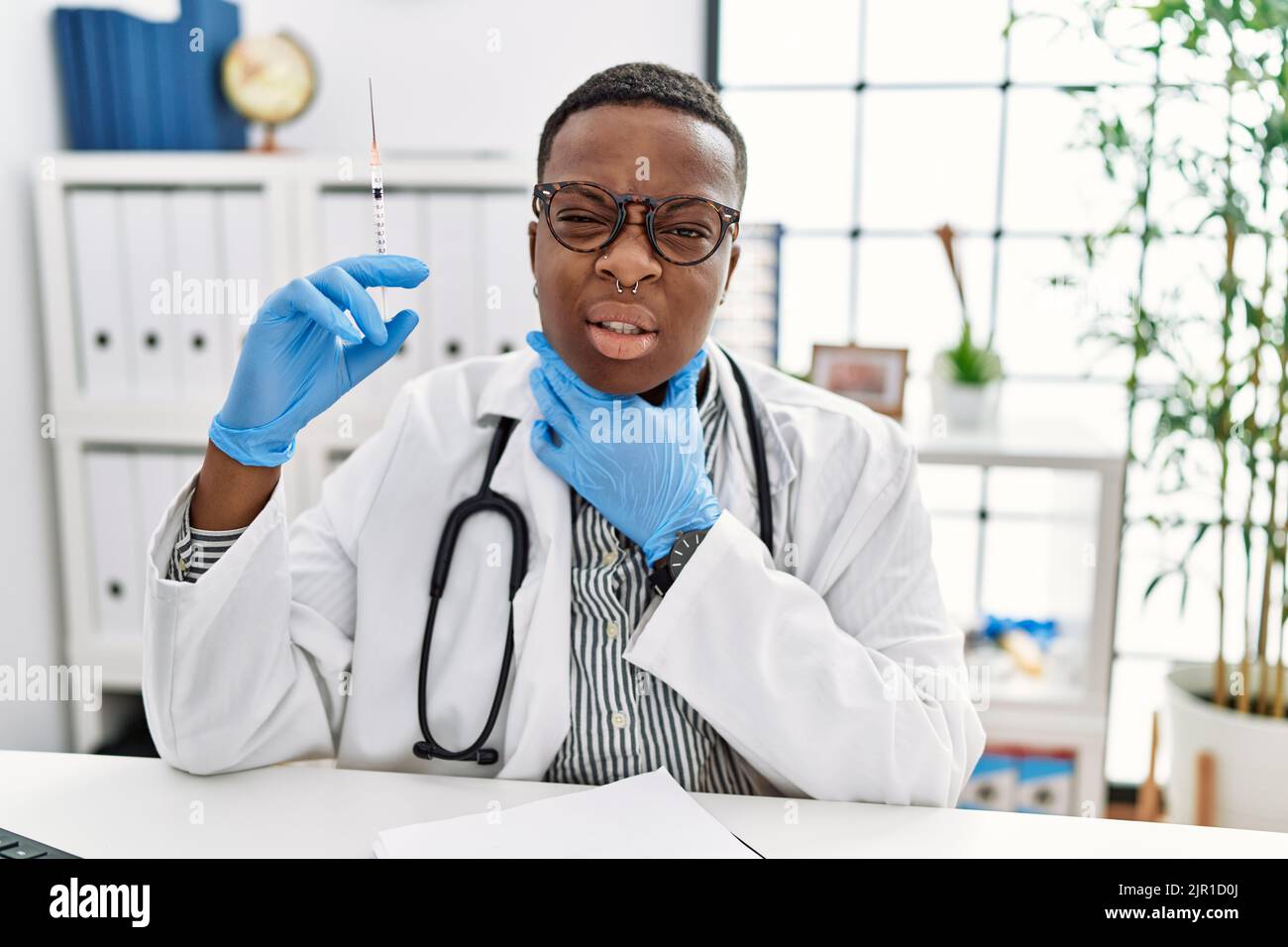 Young african doctor man holding syringe at the hospital touching ...