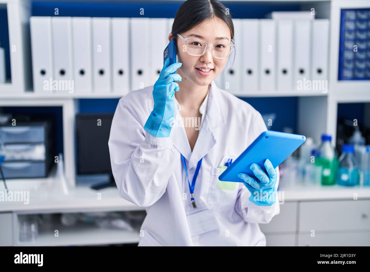 Chinese woman scientist using touchpad talking on smartphone at ...