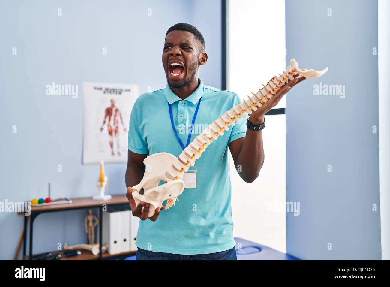 African american man holding anatomical model of spinal column angry ...