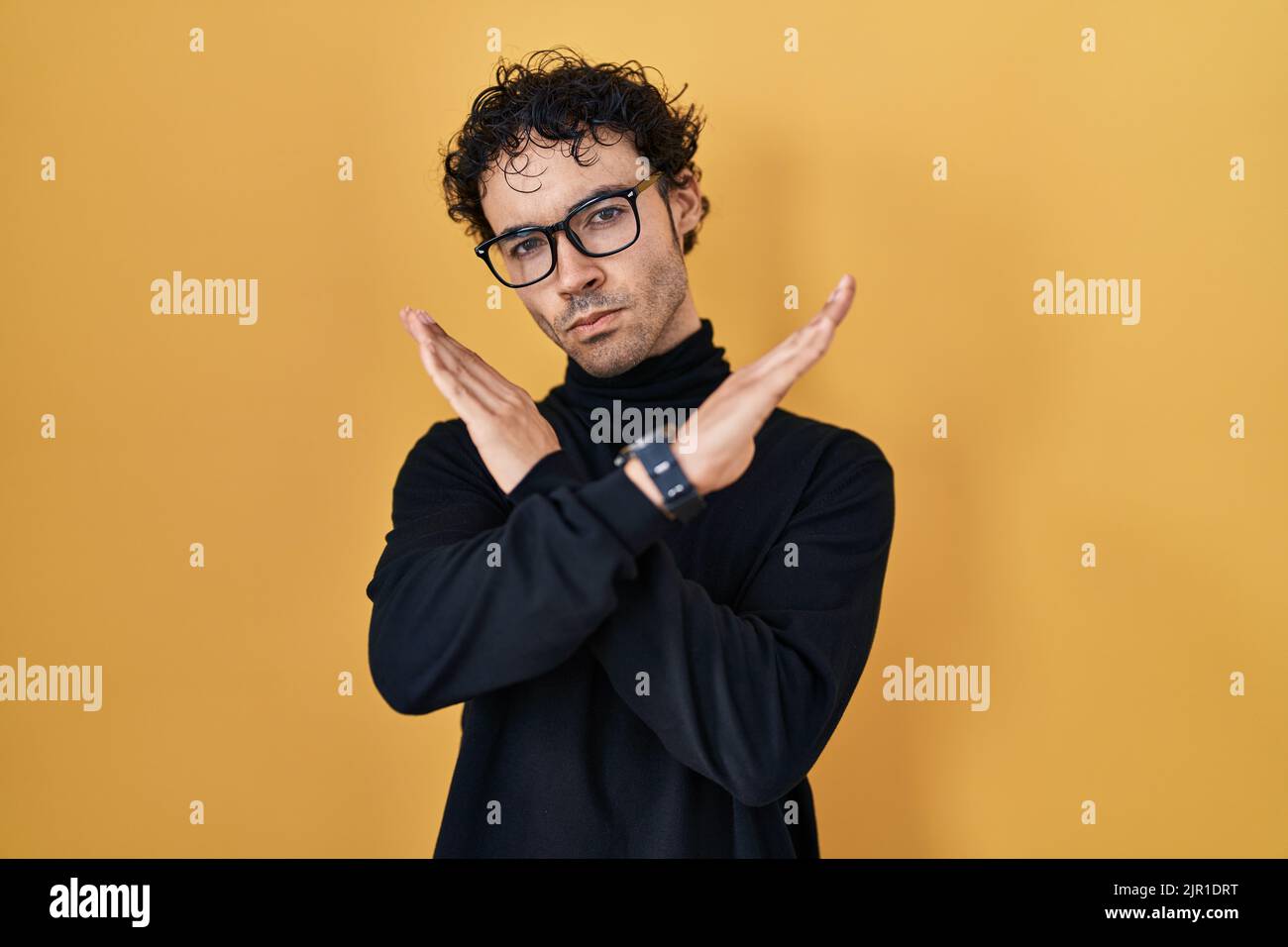 Hispanic man standing over yellow background rejection expression ...