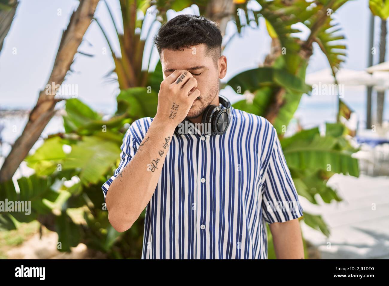 Young handsome man listening to music using headphones outdoors tired ...