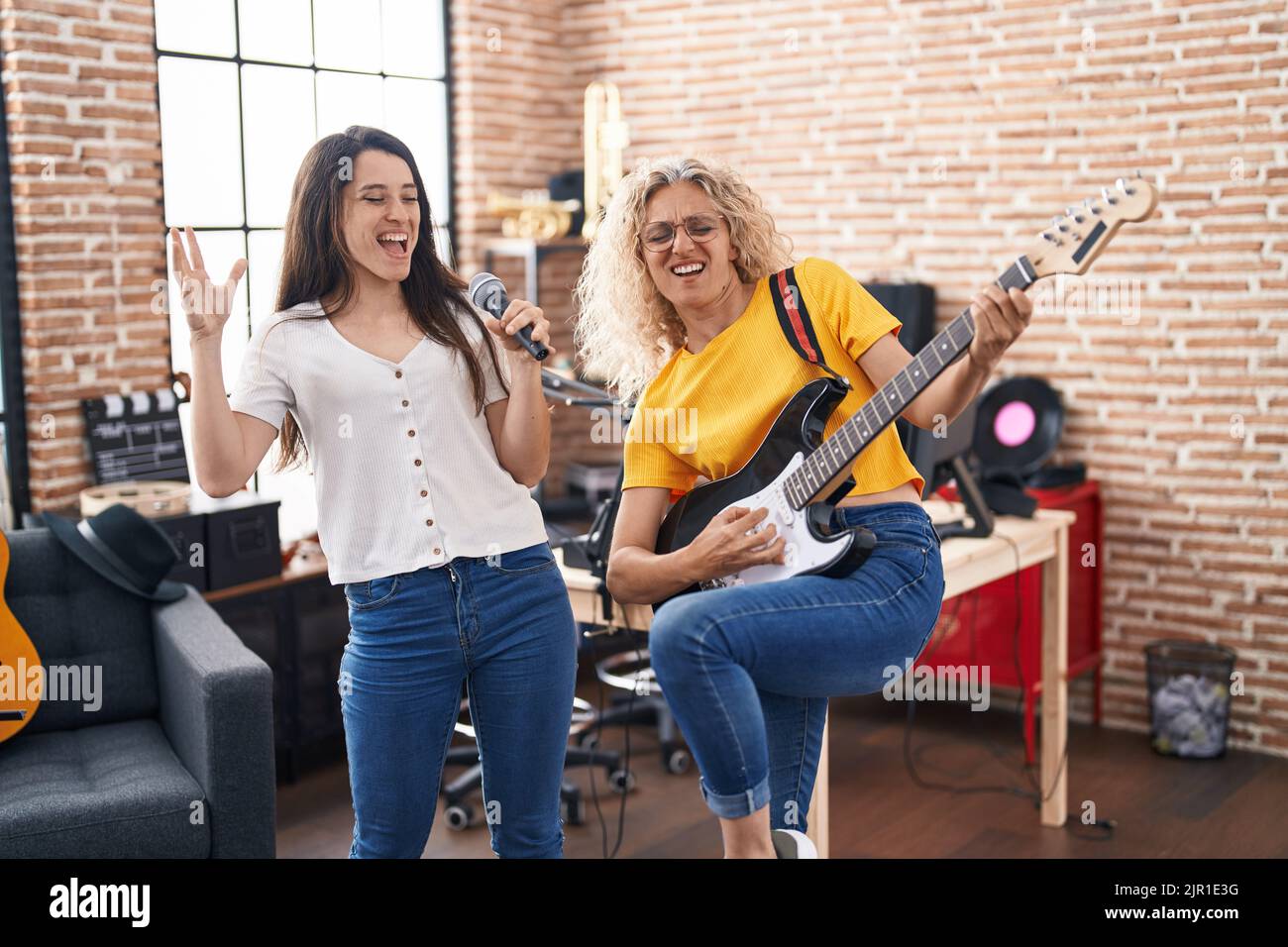 Two women musicians singing song playing electrical guitar at music ...