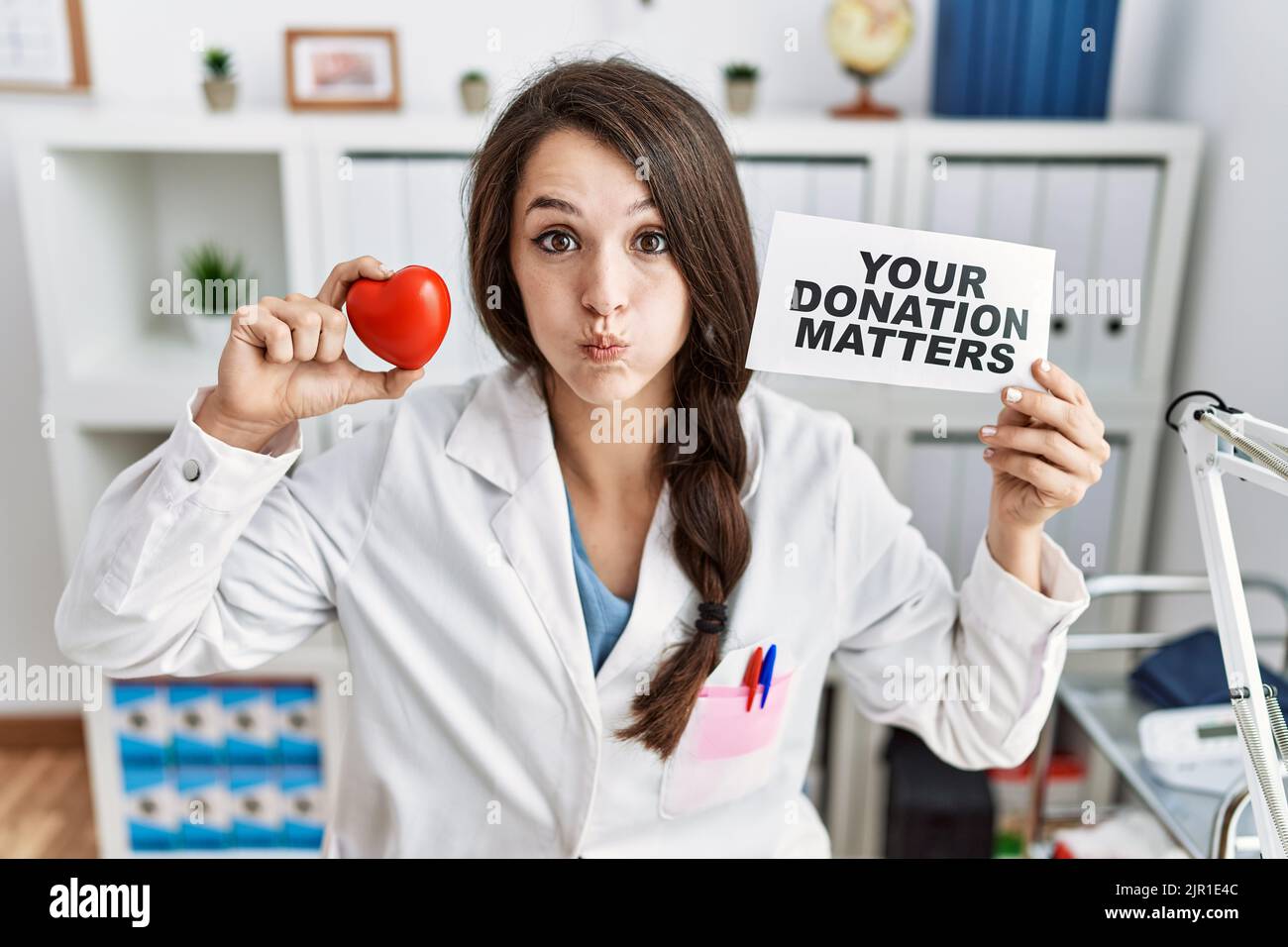 Young doctor woman holding your donation matters banner at the clinic ...