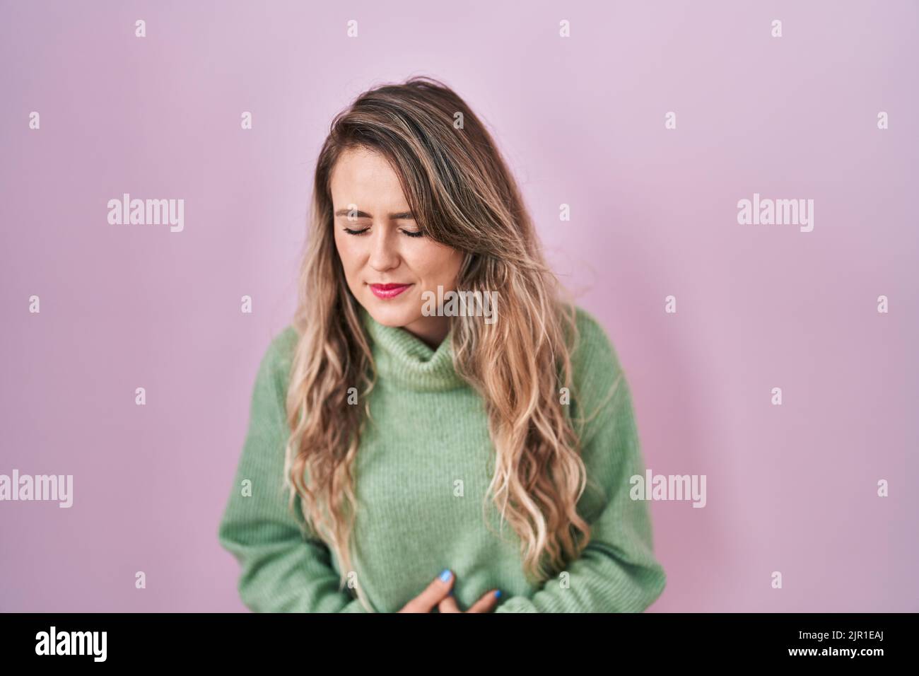 Young caucasian woman standing over pink background with hand on ...