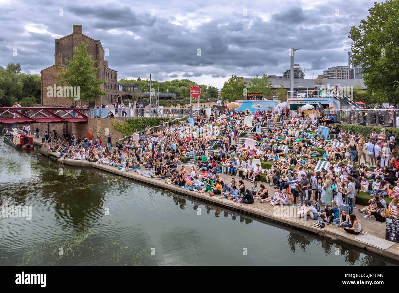 Crowds of people sitting on the canalside steps on the Regent's canal ...