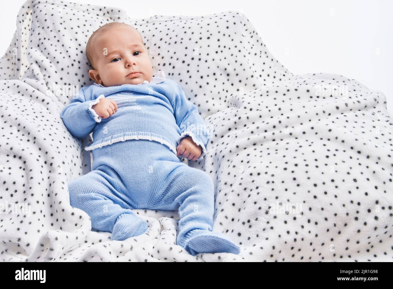 Adorable baby relaxed lying on sofa over white isolated background ...