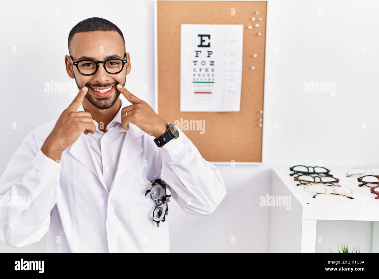 African american optician man standing by eyesight test smiling with ...