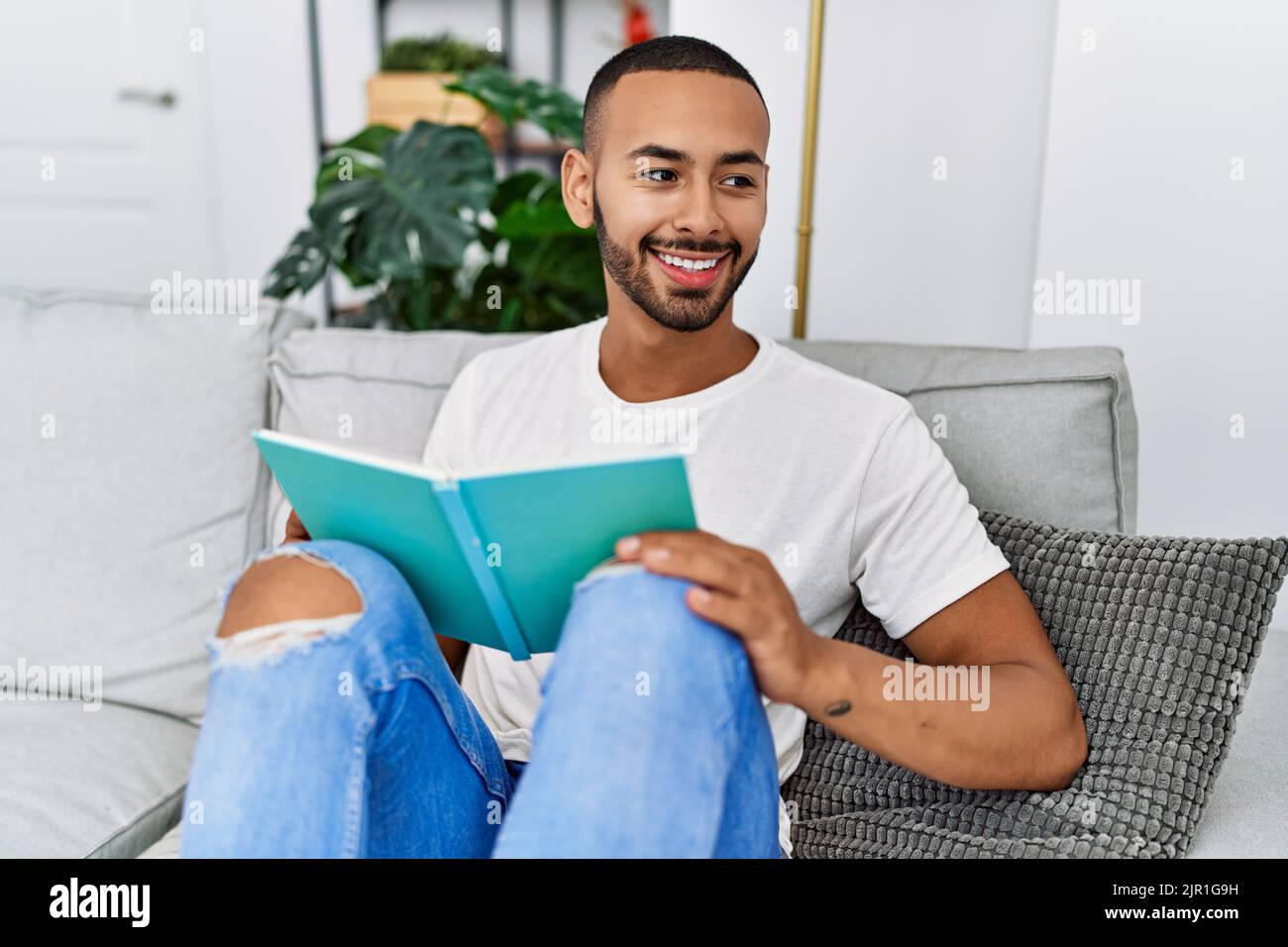 Young hispanic man smiling confident reading book at home Stock Photo ...